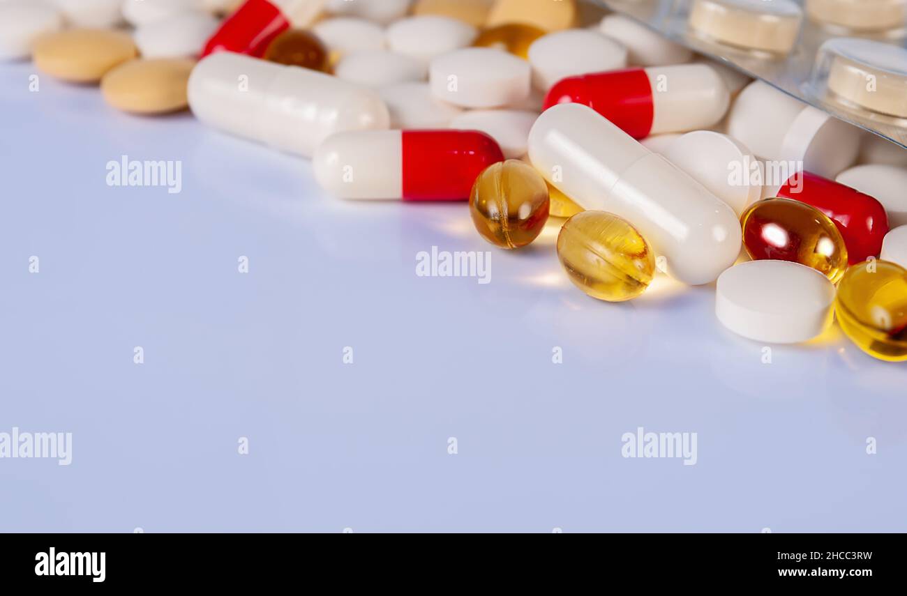 different kind of pills, tablets and capsules on light blue background ...