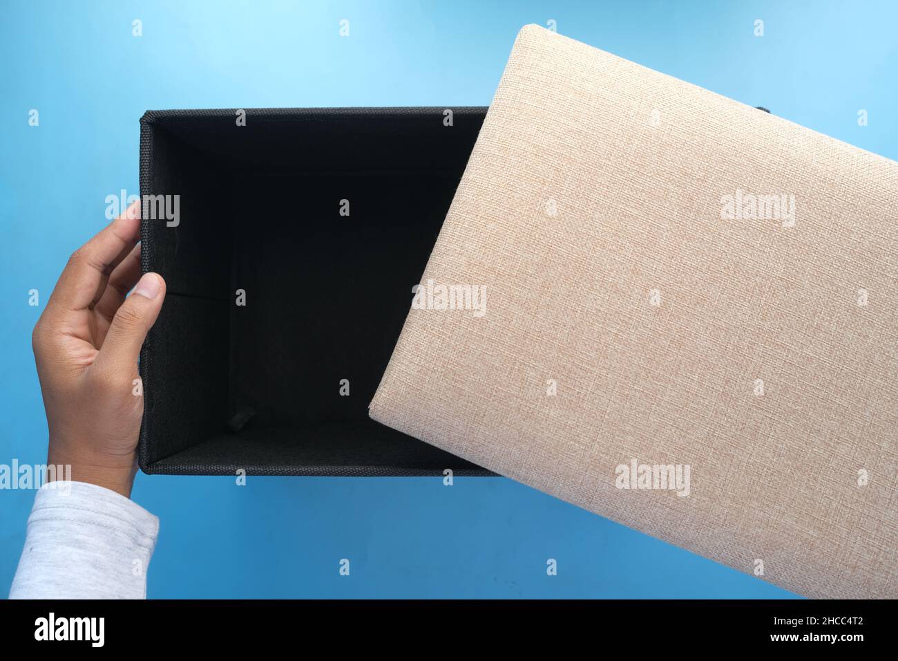 young man hand hold a box against yellow background Stock Photo - Alamy