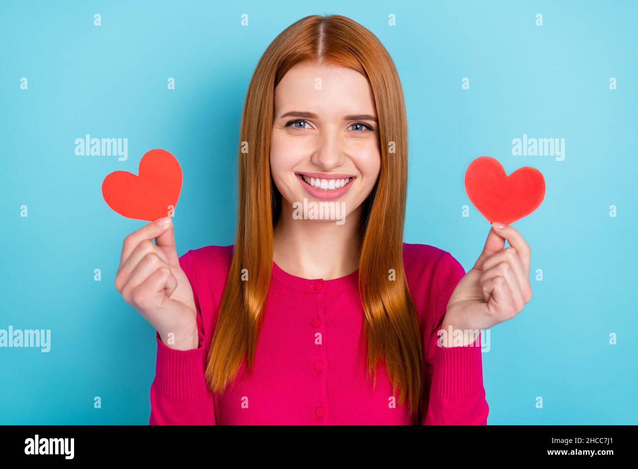 Portrait Of Attractive Cheerful Red Haired Girl Holding Two Heart Signs