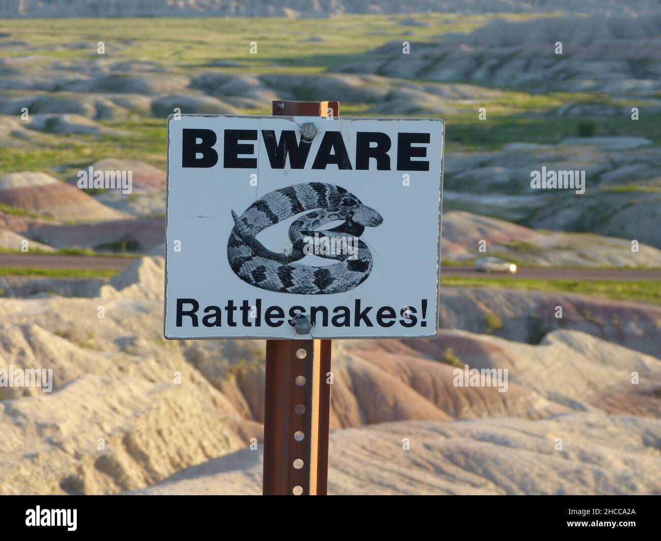 Signboard with a warning text "beware rattlesnakes in Badlands National ...
