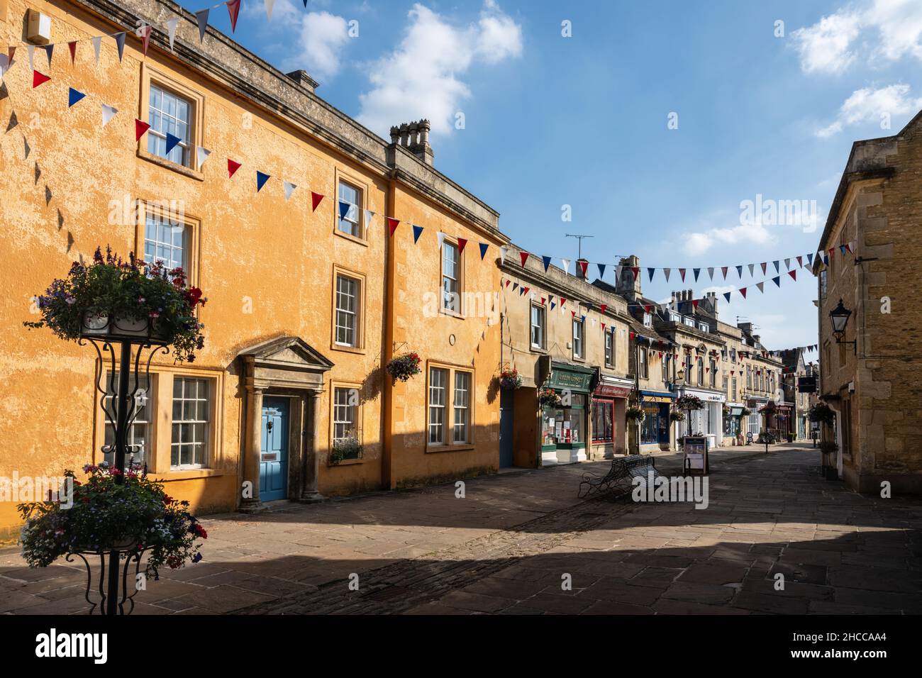 Shops and offices are decorated with bunting and flower baskets on the ...