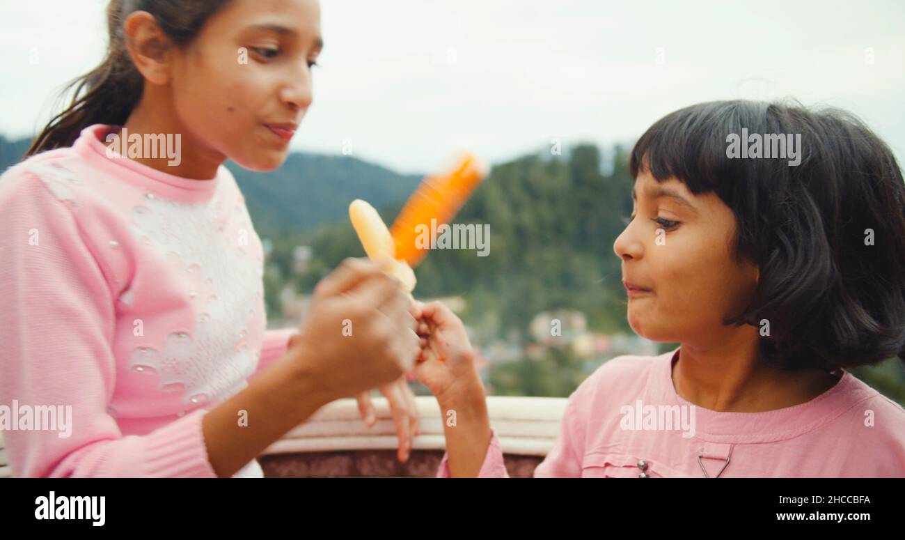 Close-up shot of South Asian girl's eating an orange ice-cream Stock ...