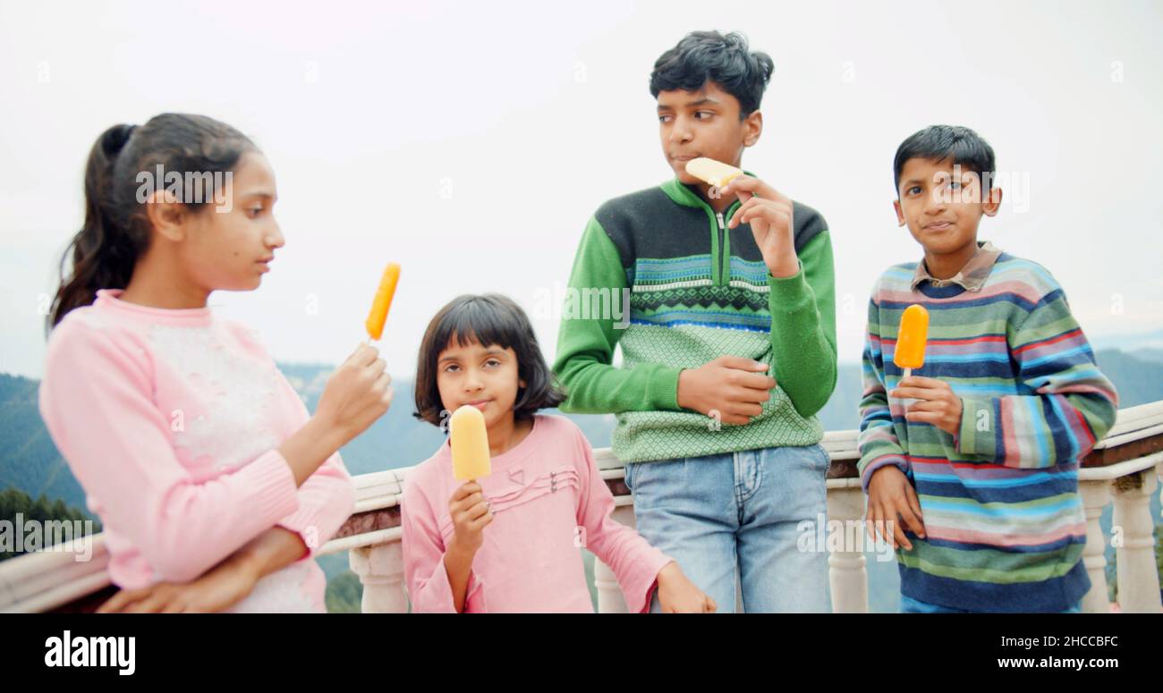Group of young South Asian friends eating orange ice creams against the ...