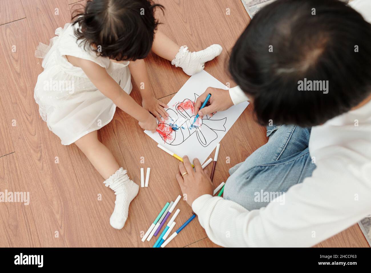 Father helping little daughter to color picture of candy cane for ...