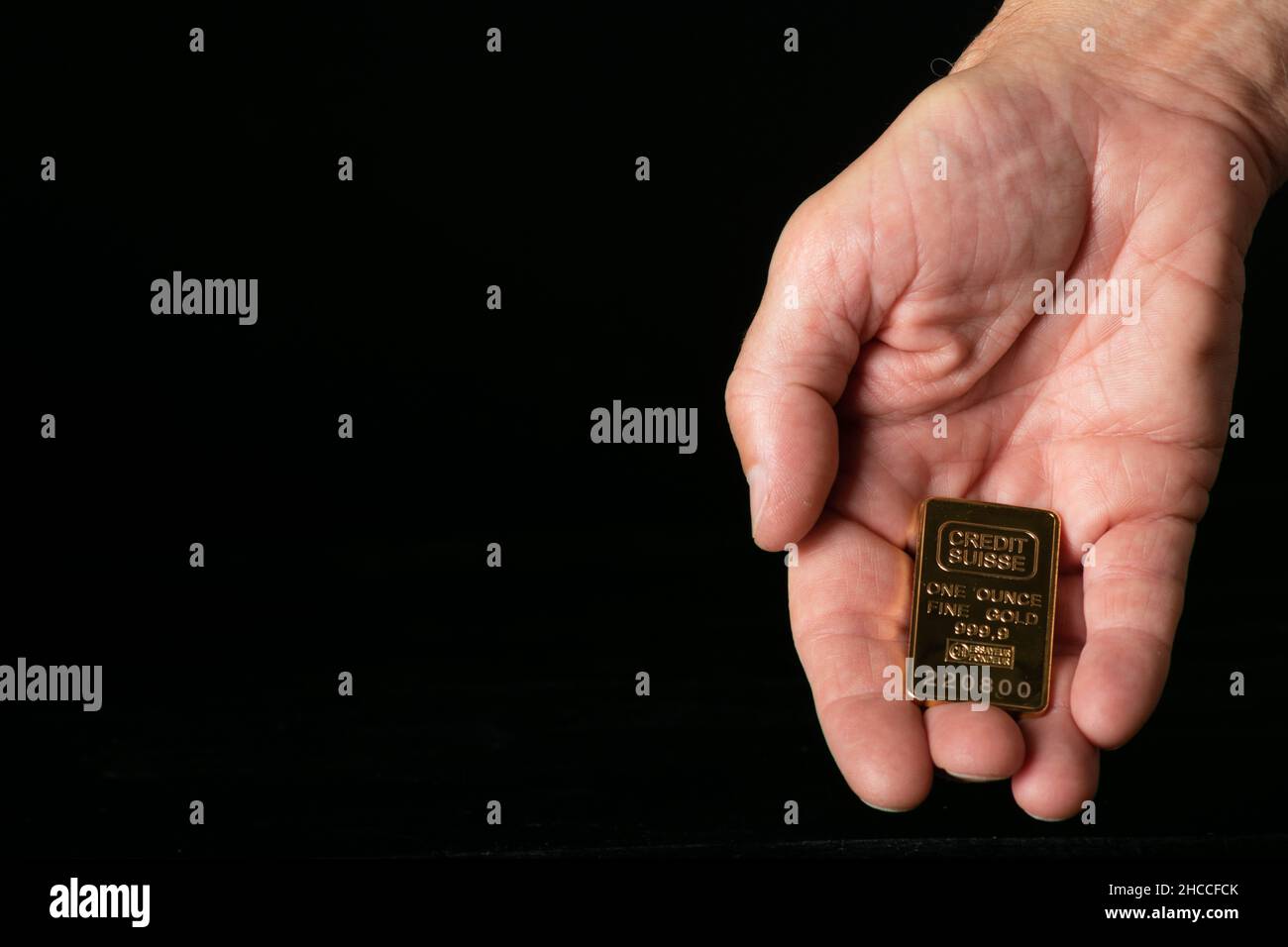 Hand on black background holding a small gold ingot Stock Photo - Alamy