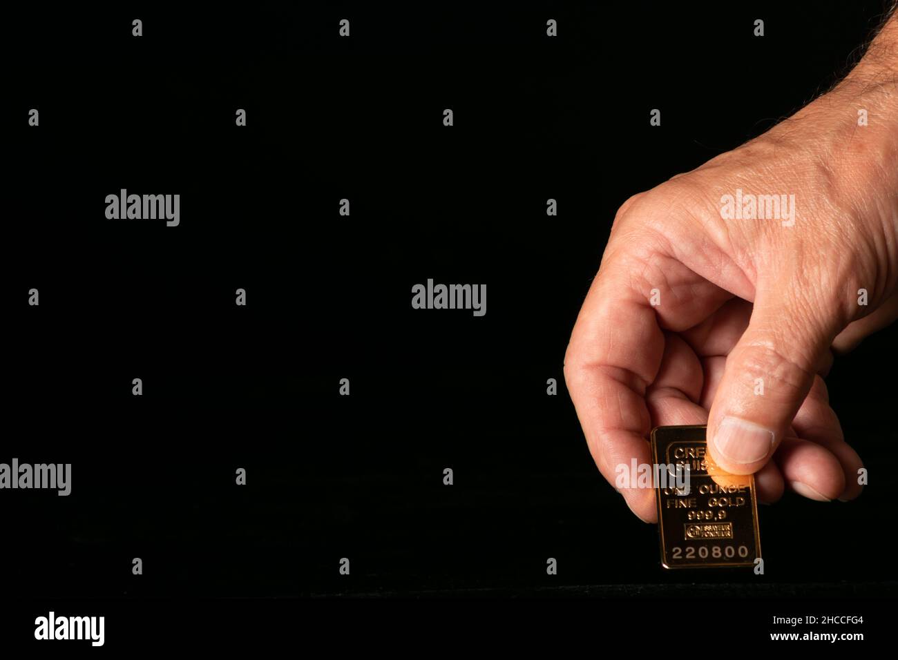 Hand on black background holding a small gold ingot Stock Photo - Alamy