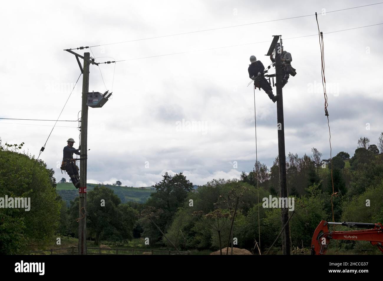Power workers working on utility pole and connecting electricity lines ...