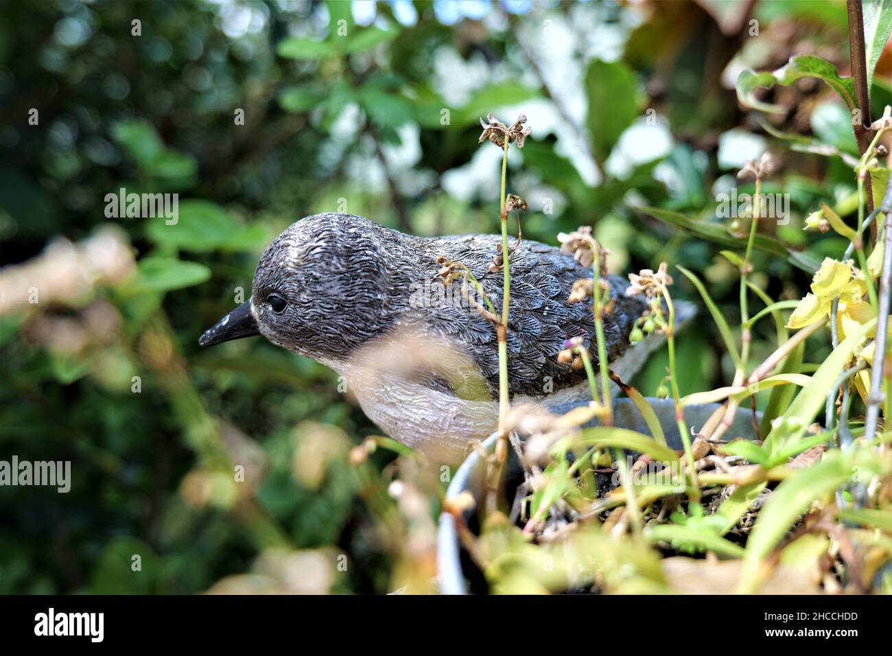 Closeup shot of the artificial bird statue in the park against a green ...