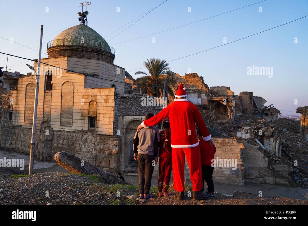 A man dressed as Santa Claus stands in front of the damaged Umayyad ...