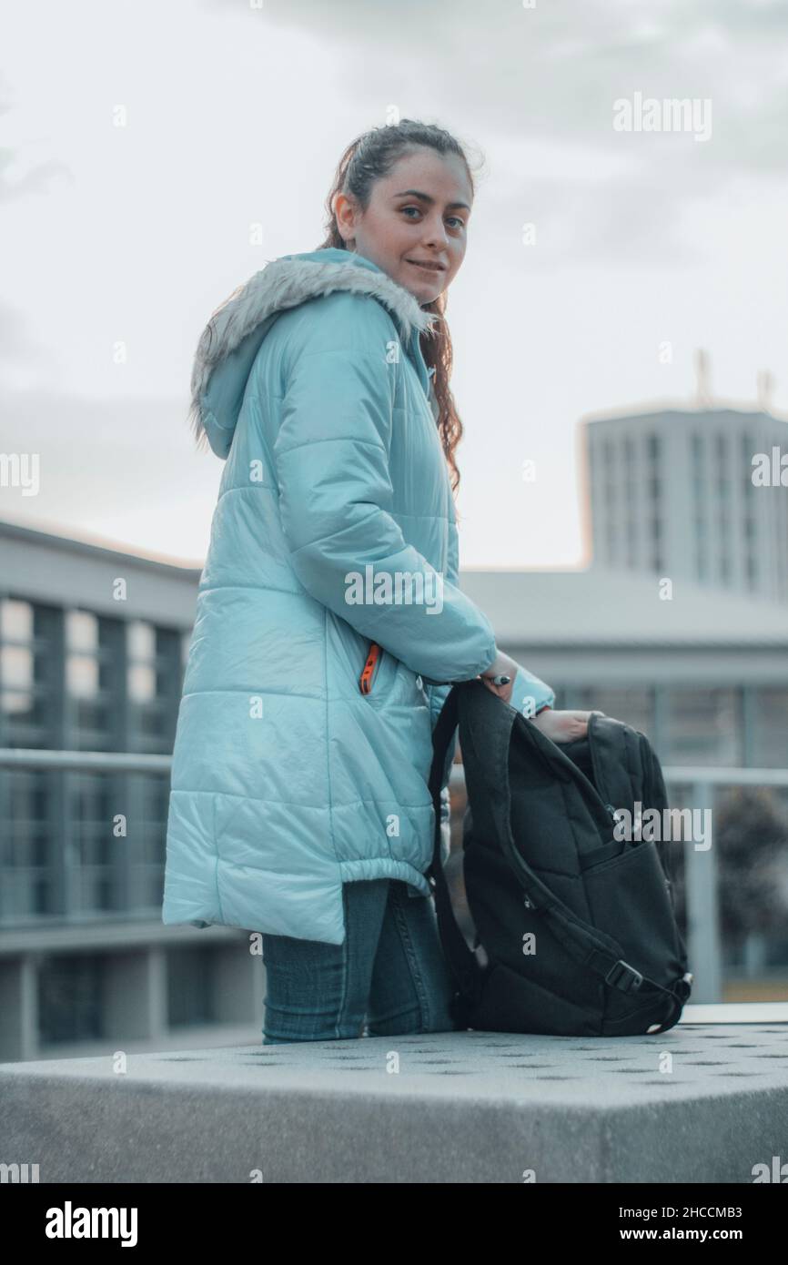 School teenage girl with jacket picking up her backpack at school in a ...