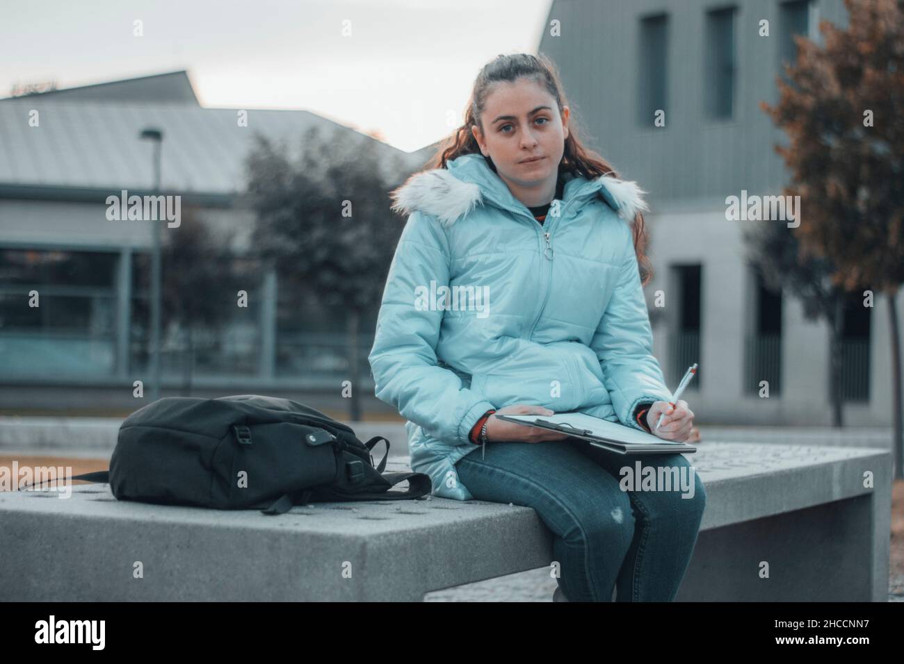 Teenage college student writing and taking class notes in her break ...