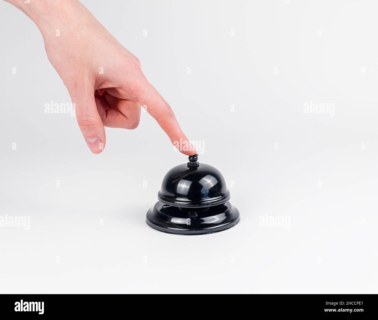 Desk bell is pressed by female hand. Concept image on white background ...