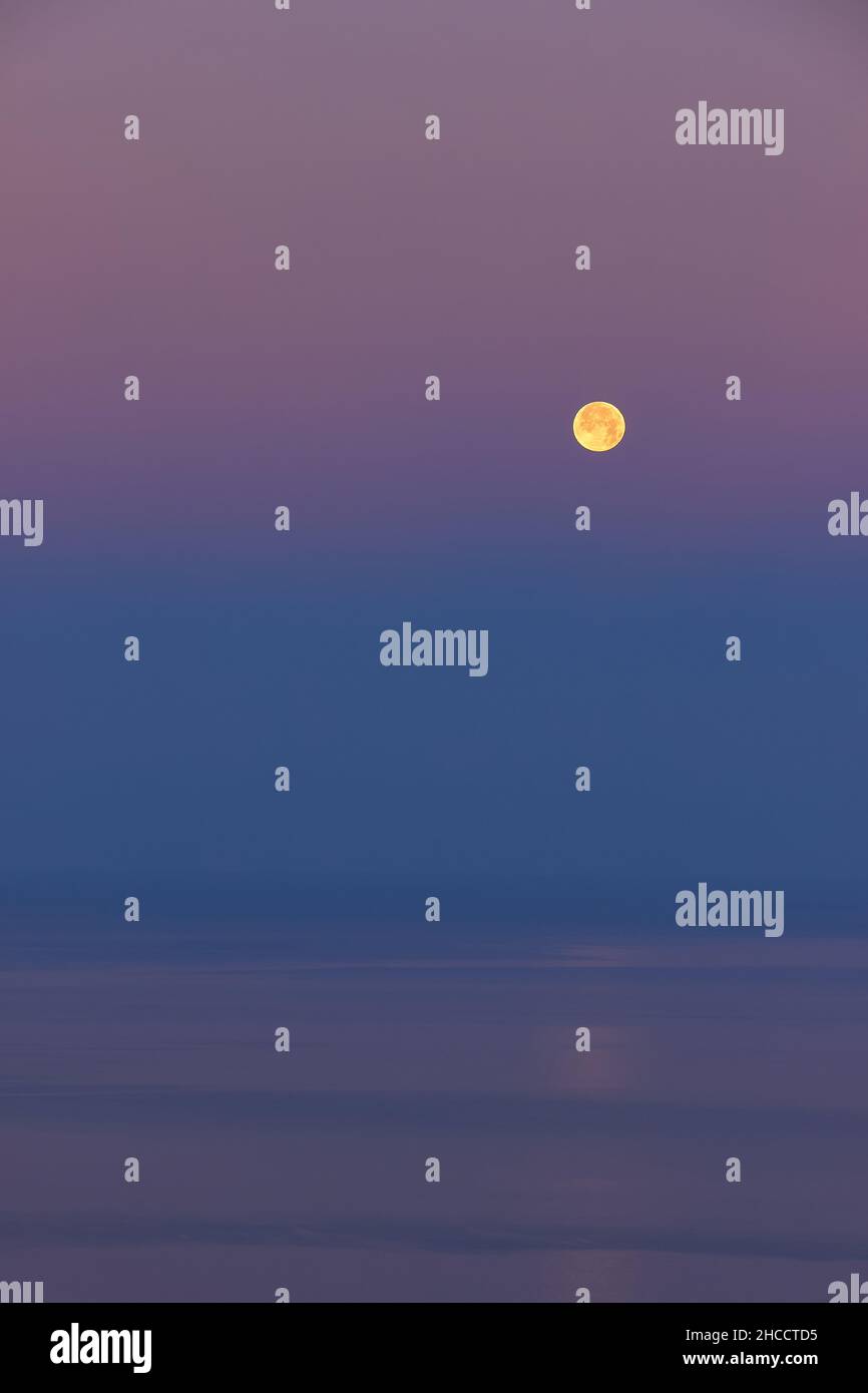 vertical image of the full moon over the sea horizon, there are soft ...