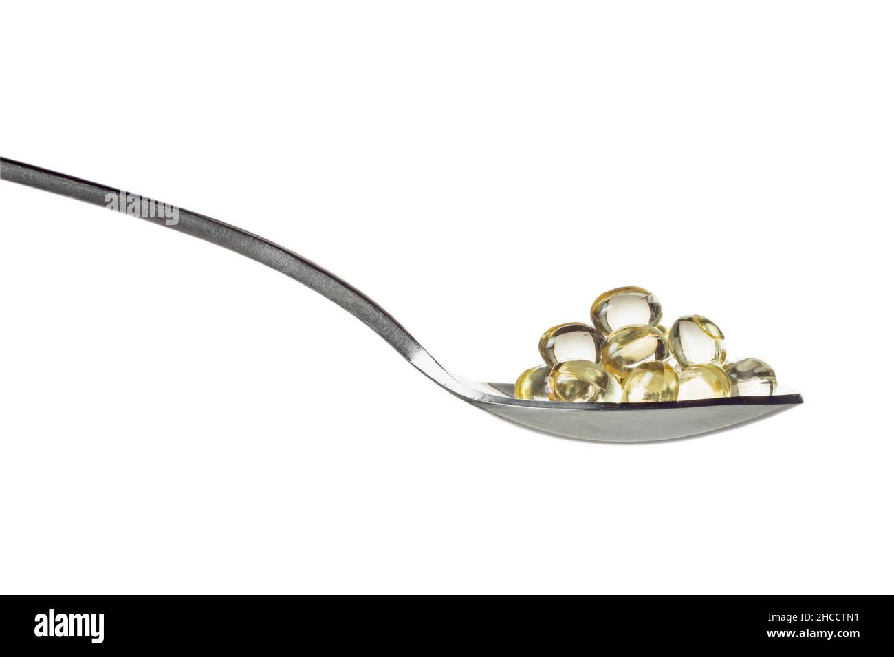 White transparent capsules with vitamins or medicine in spoon isolated ...