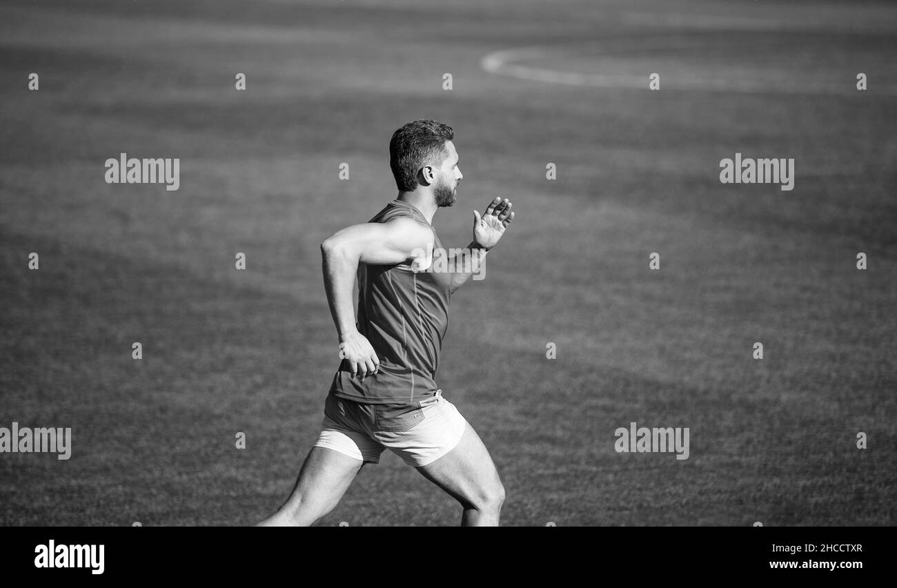 energetic athletic muscular man runner running outdoor on green grass ...