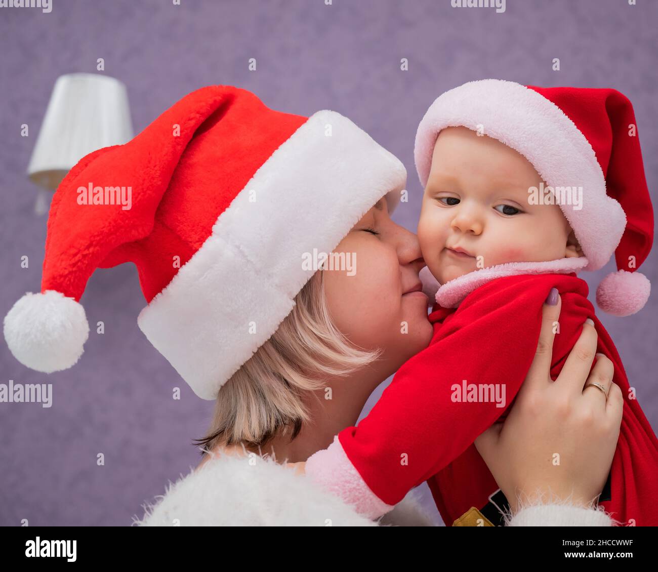 Caucasian woman hugging baby son in santa claus costume Stock Photo - Alamy