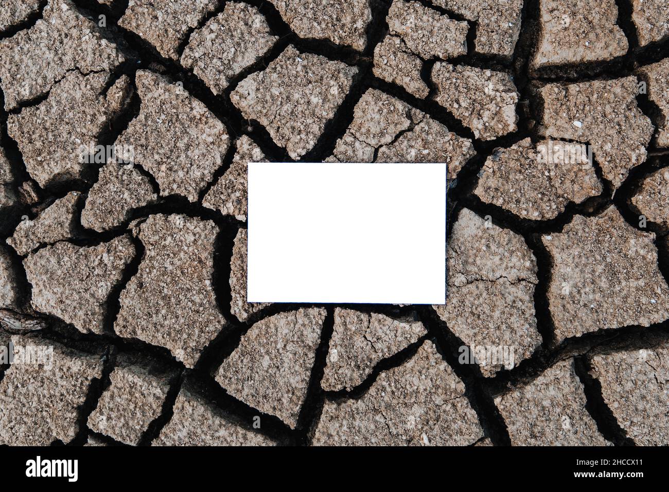 A white sheet of paper lies against the background of a barren, cracked ...