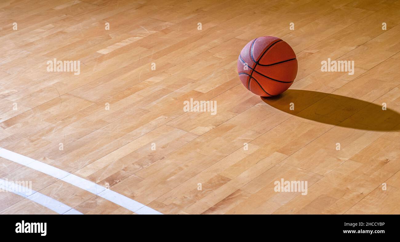 Basketball on hardwood court floor with natural lighting. Workout ...