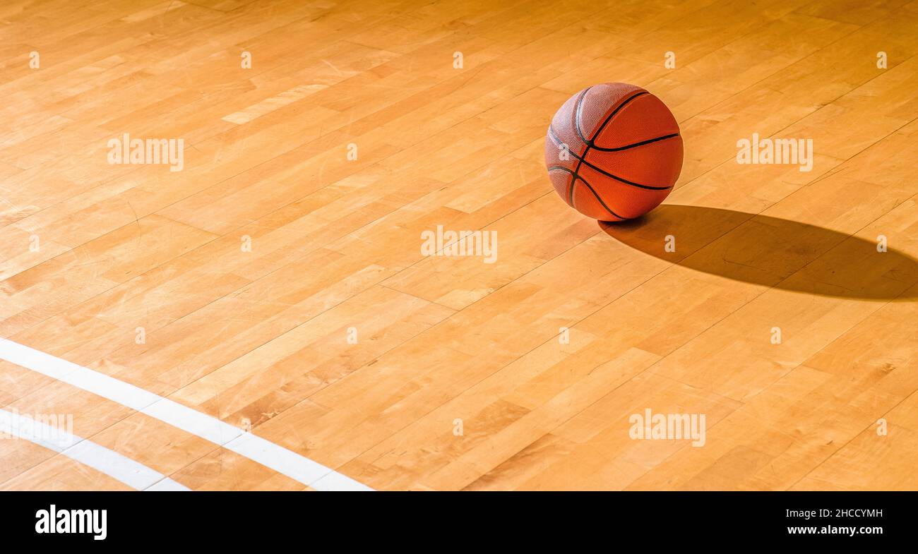Basketball on hardwood court floor with lighting. Workout online ...