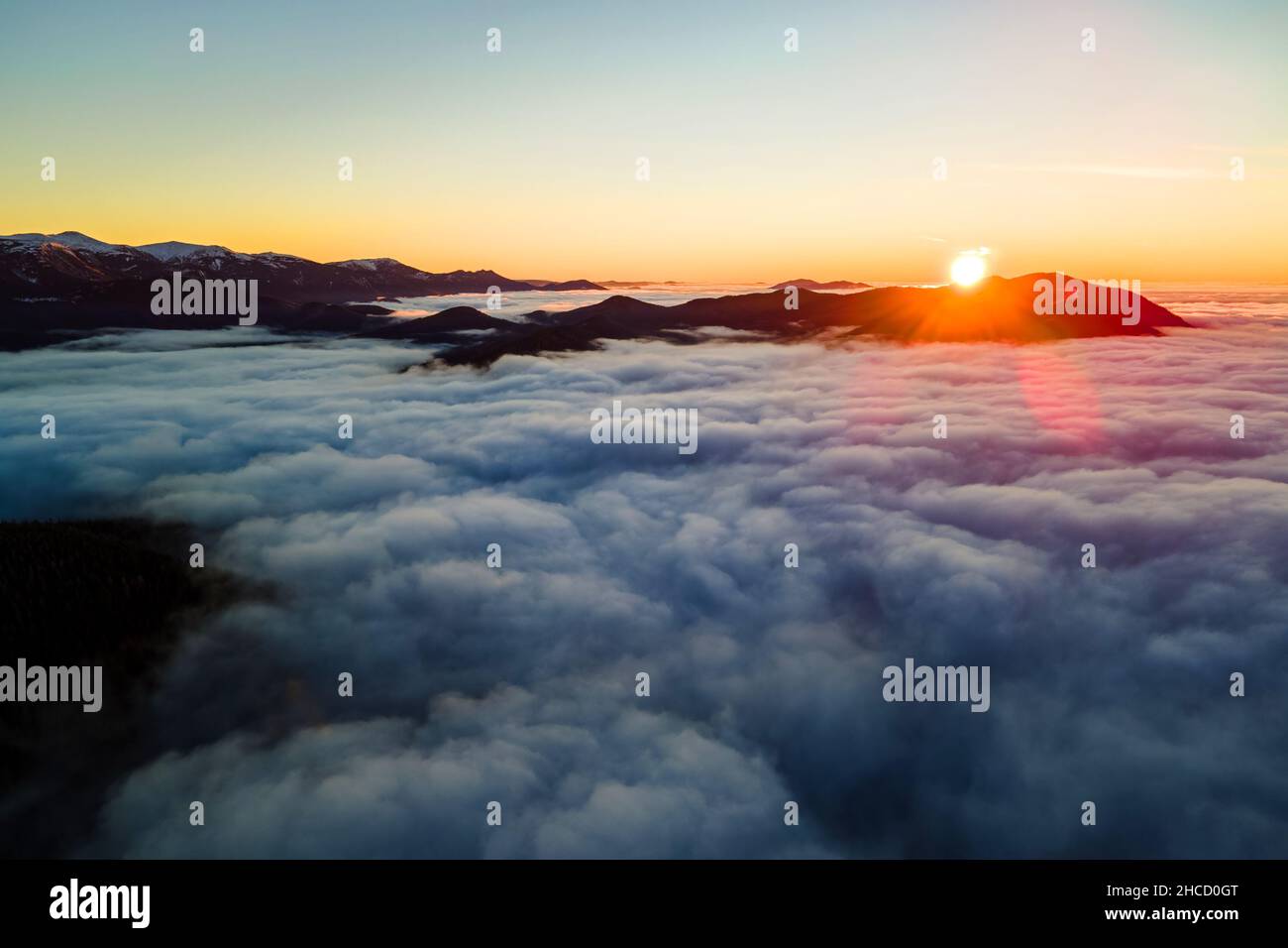 Aerial view of vibrant sunrise over white dense clouds with distant ...