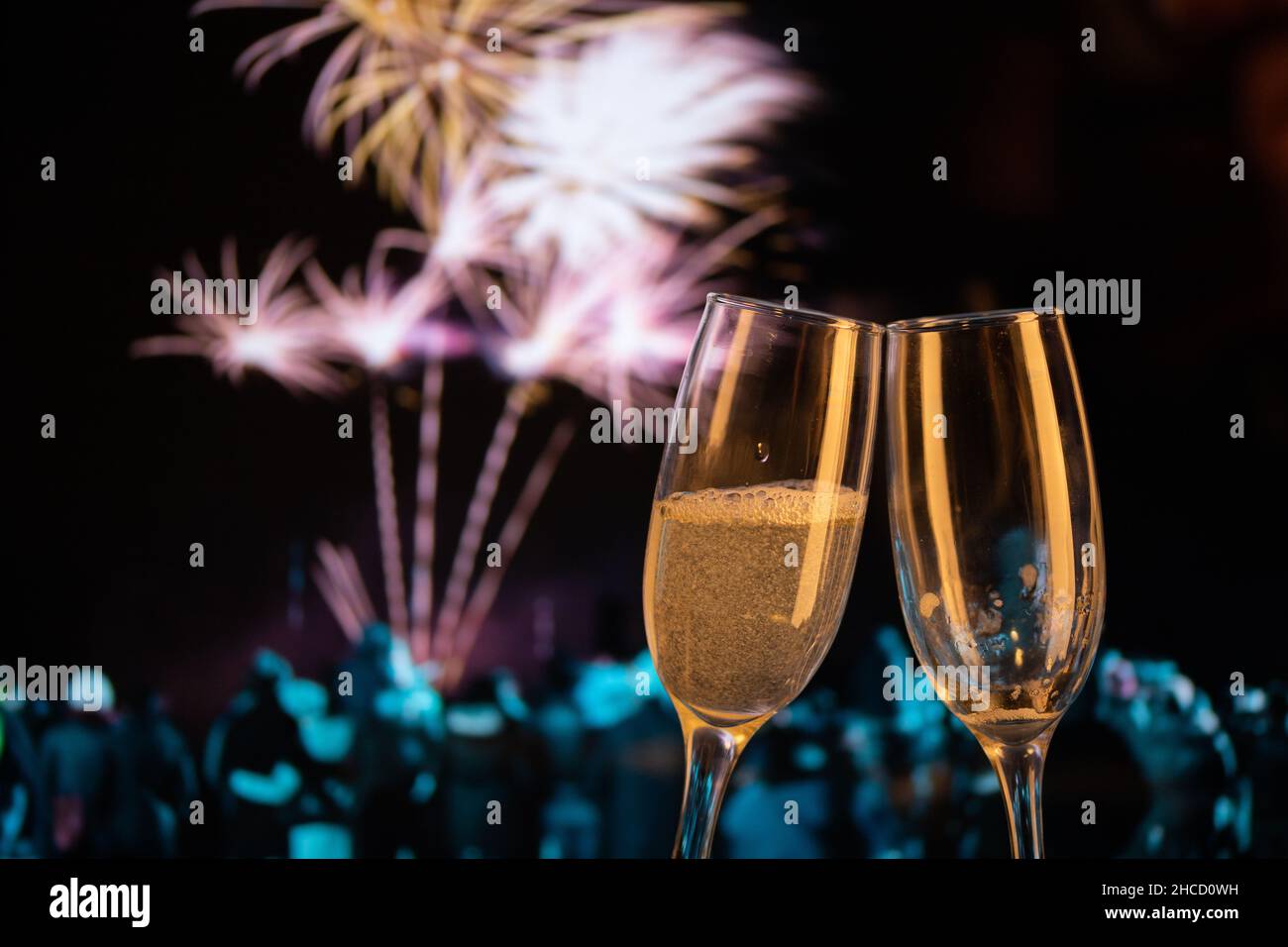 two champagne glasses against fireworks New Year's eve celebration ...