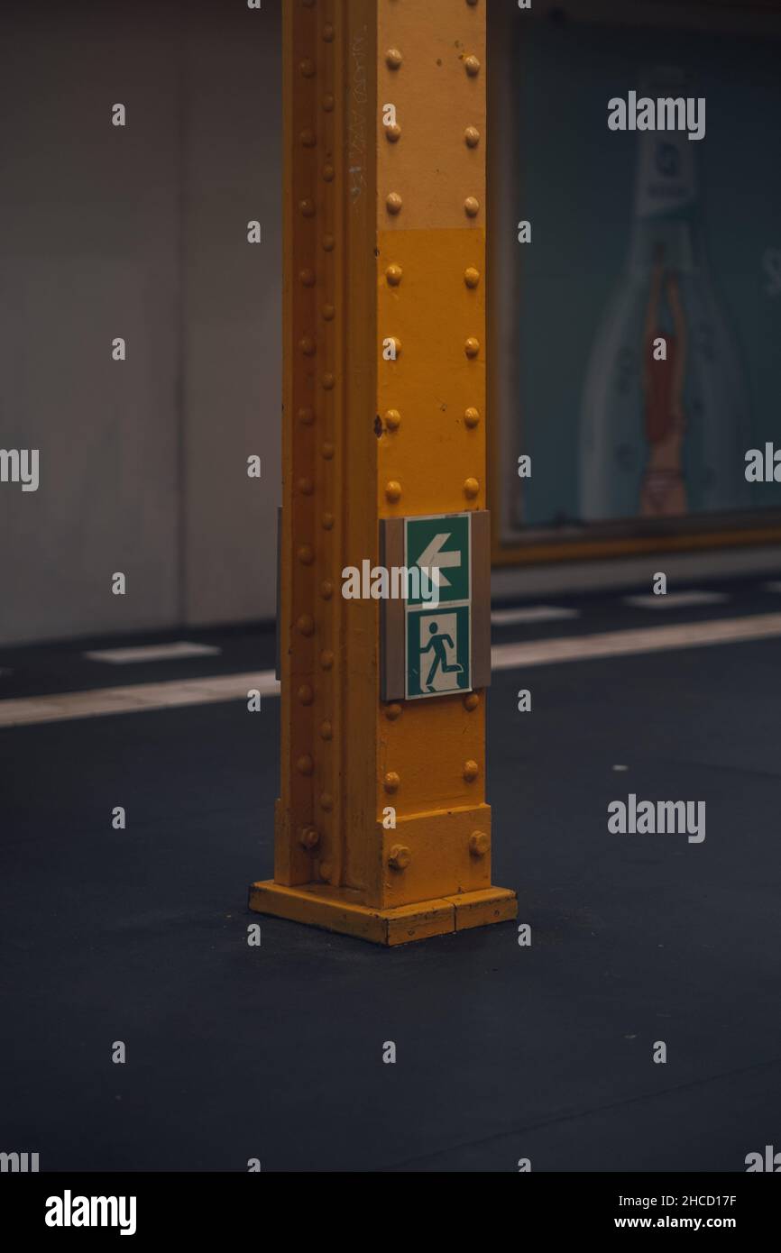 Vertical shot of a yellow post with a green exit sign and an arrow ...