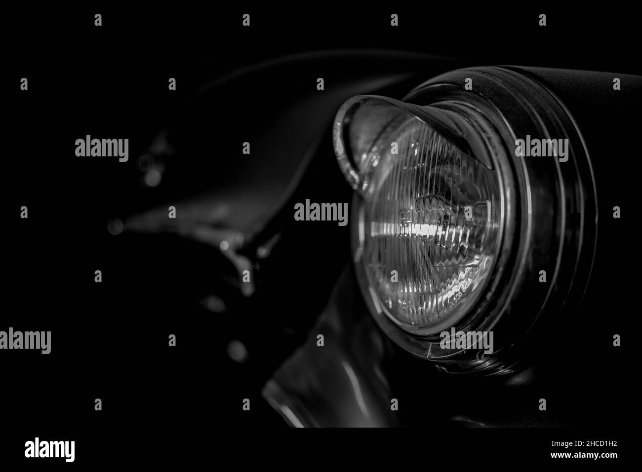 Closeup of a headlight of a classic black car with a black background ...