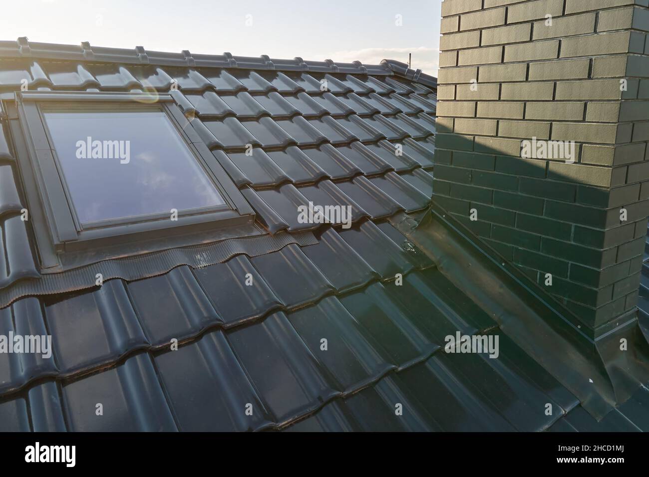 Closeup of attic window and brick chimney on house roof top covered ...