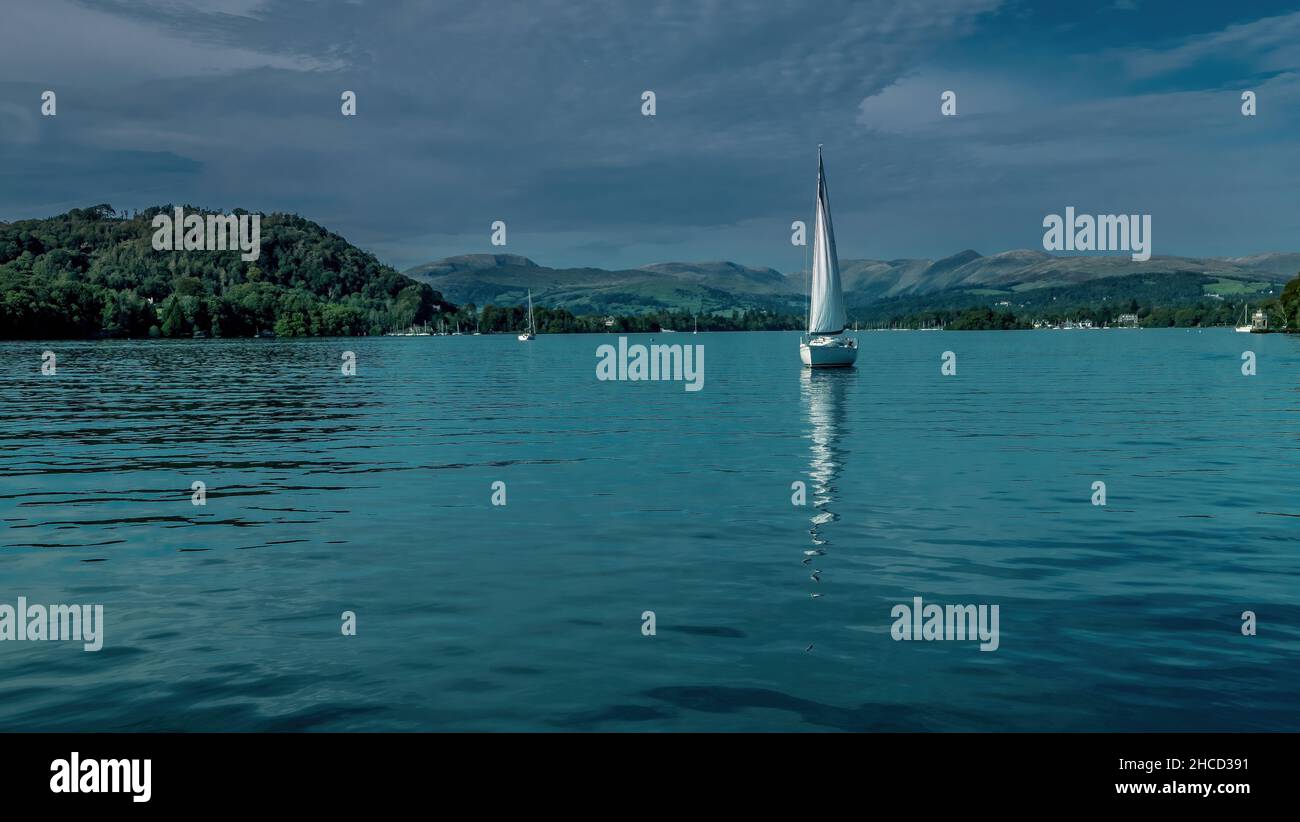 Small boat sailing in a lake surrounded by hills and mountains Stock ...