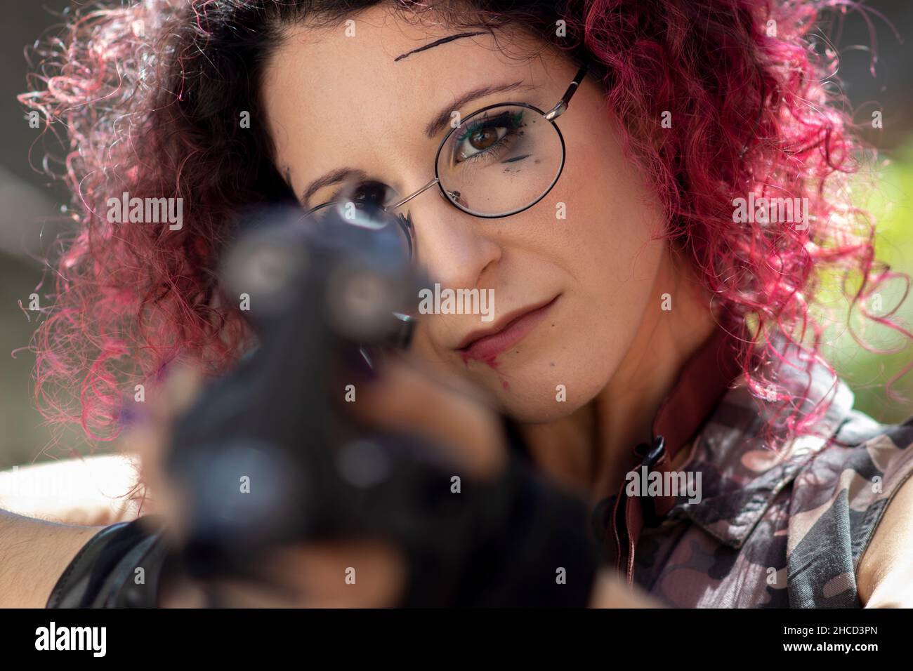 Young girl with pink hair and glasses holding a gun Stock Photo - Alamy