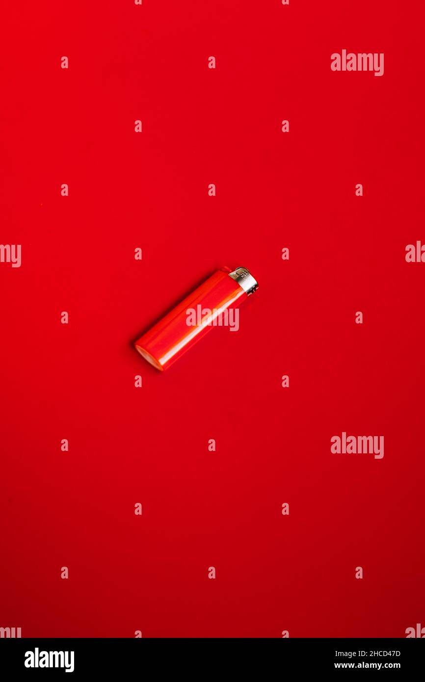 Vertical shot of a red lighter isolated on a matching background with ...