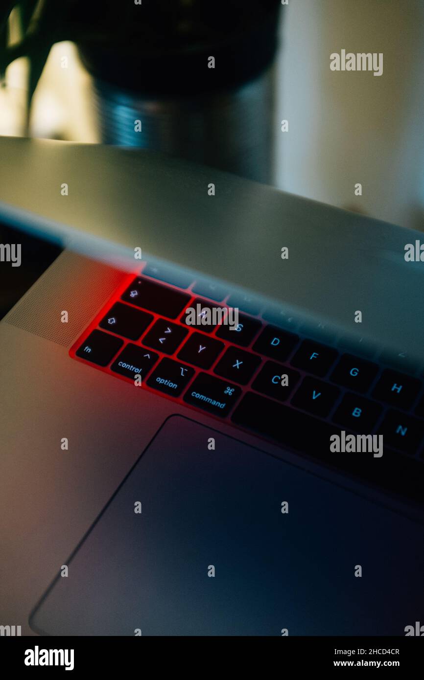 Vertical shot of a half-opened laptop keyboard with under the red light ...