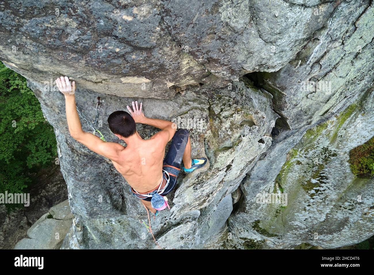 Young man climbing steep wall of rocky mountain. Male climber overcomes ...