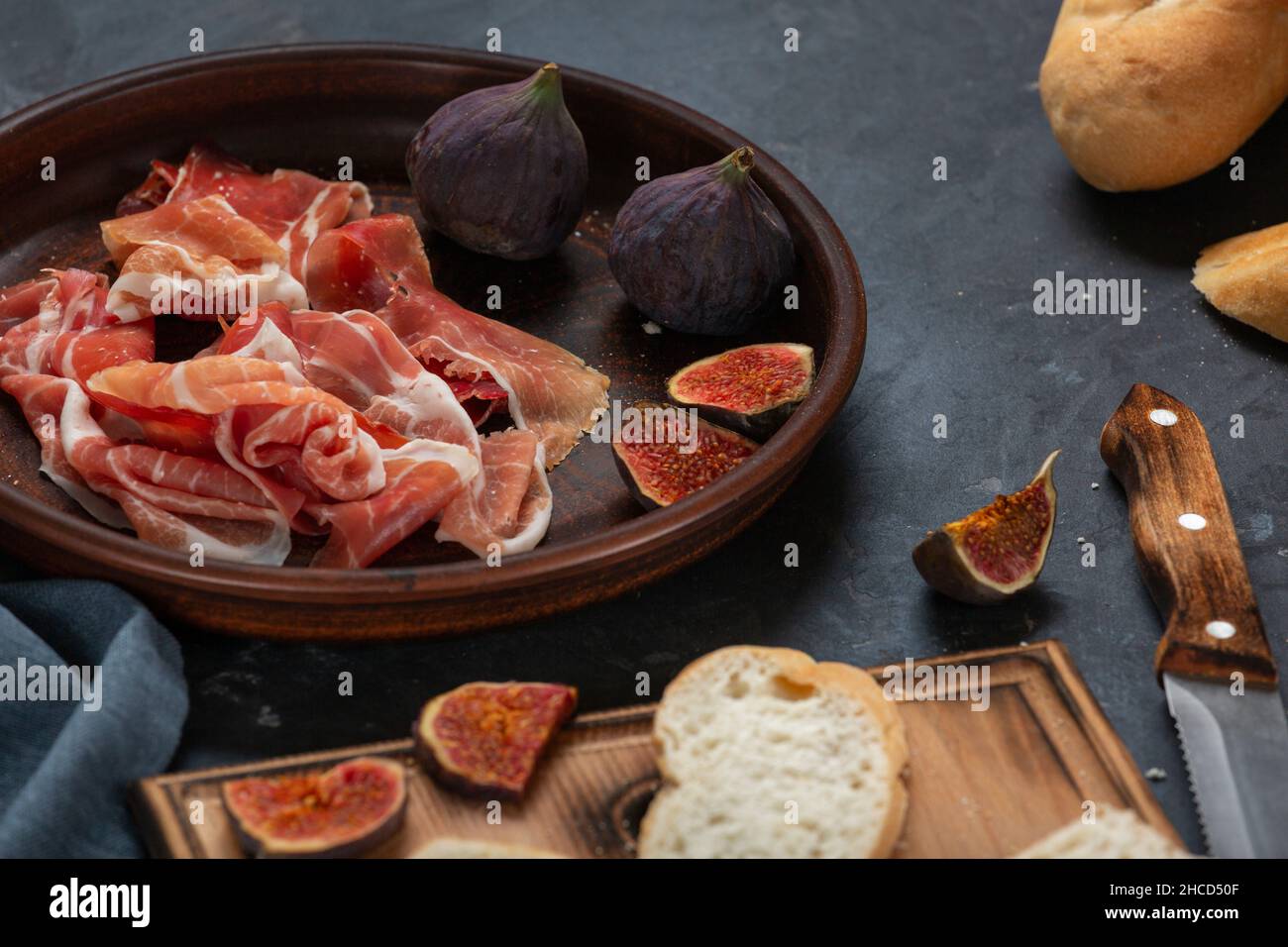 Jamon with figs and a baguette with cream cheese on the dining table ...
