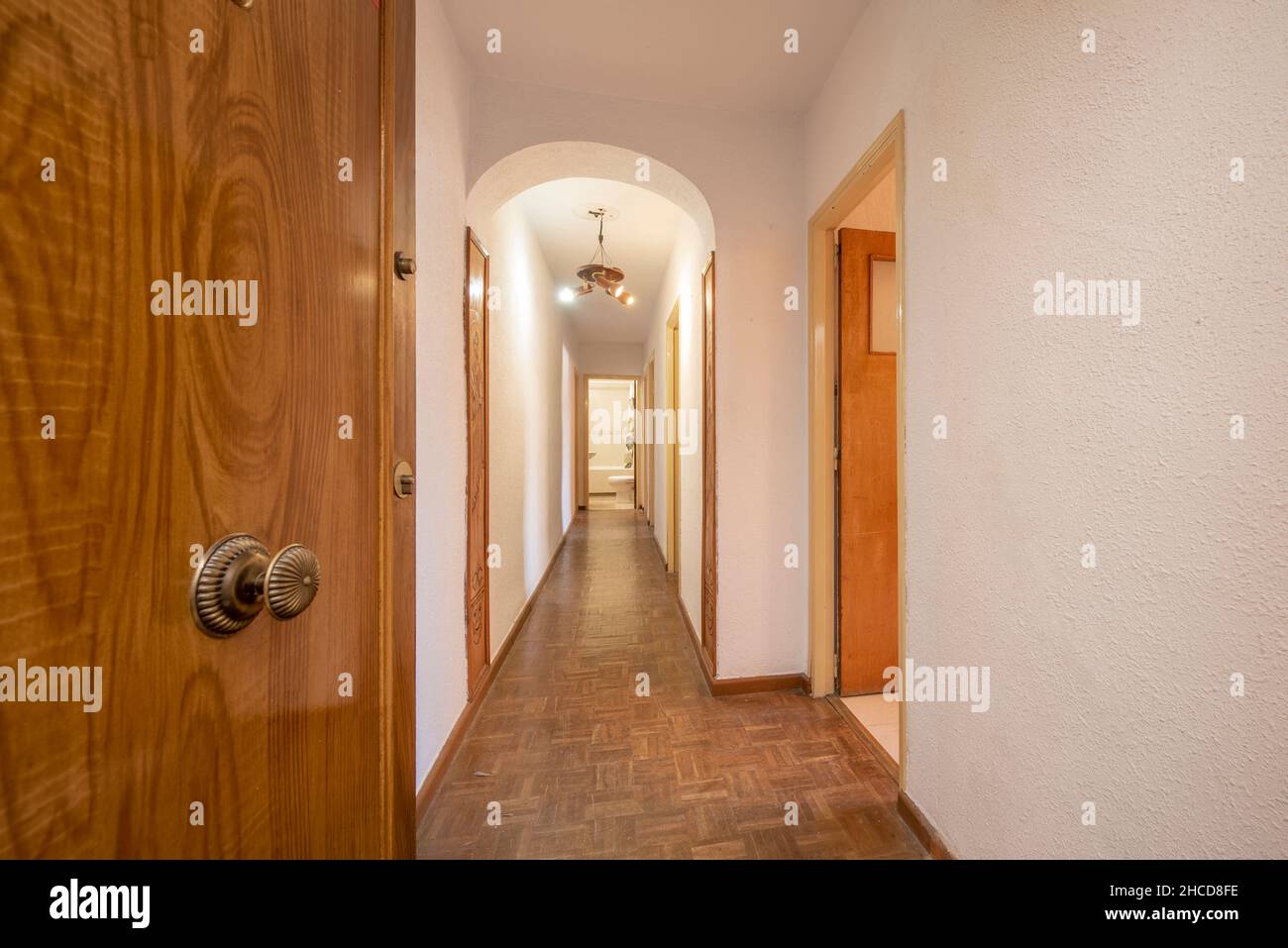 Wooden entrance door to a home with a long corridor flanked by pine ...