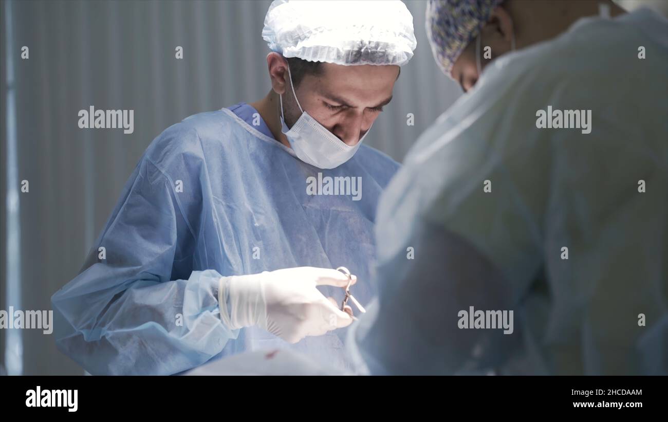 Close up of male surgeons at work. Side view of concentrated doctors ...