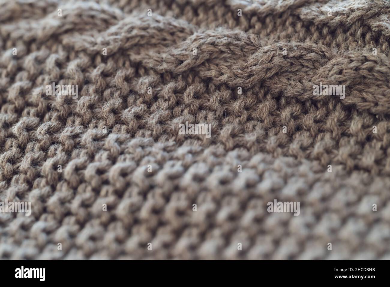 Close-up of a light brown cable knit sweater with detailed yarn texture ...