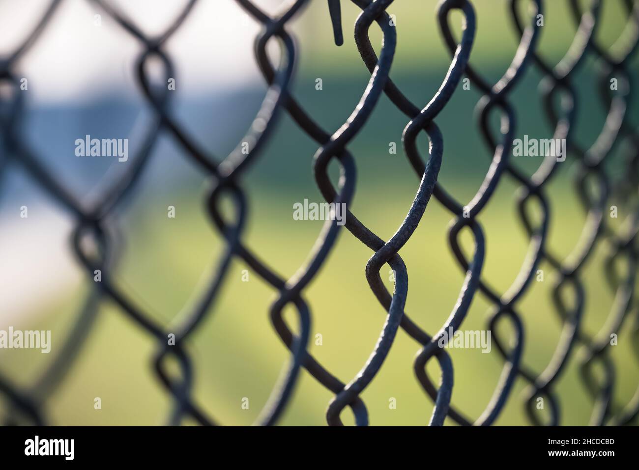 Abstract closeup on a rusty chain link fence against a green and blue ...