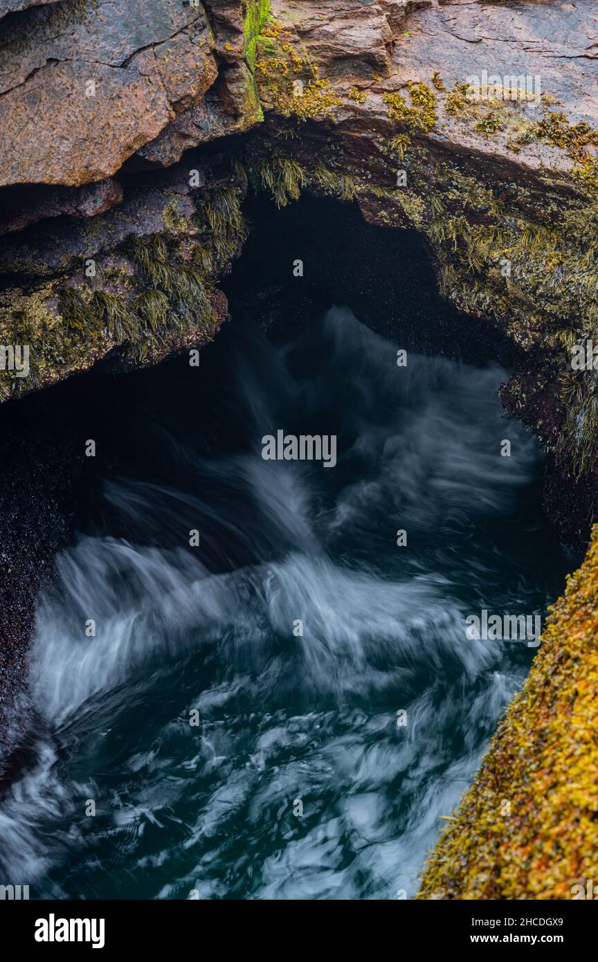 Rising tide waves crashing into a natural rock inlet called Thunder ...