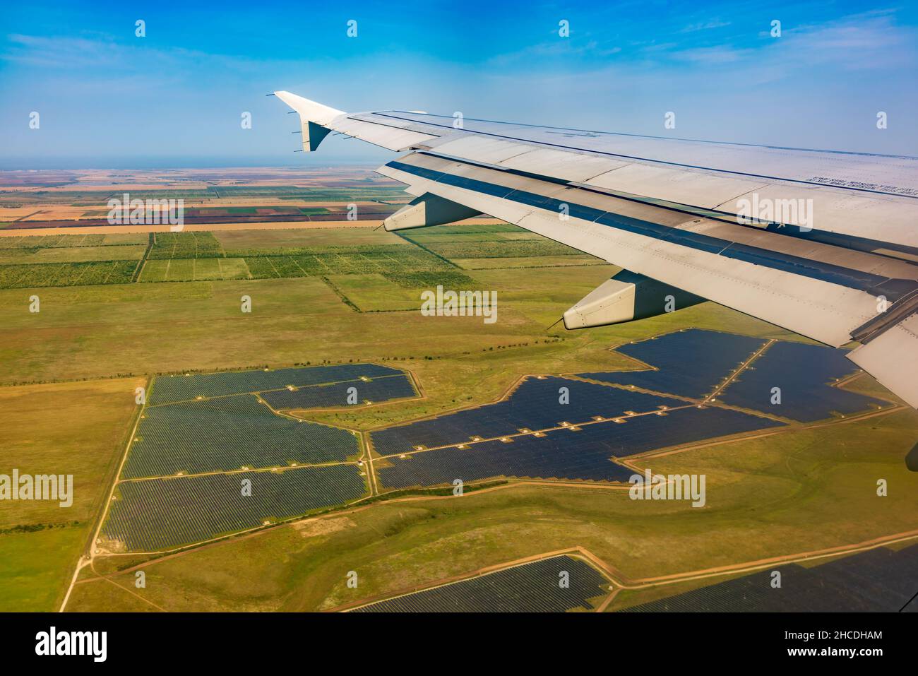 View of airplane wing, blue skies and green land during landing ...