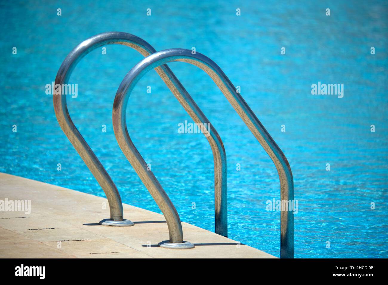 Close up of swimming pool stainless steel handrail descending into ...