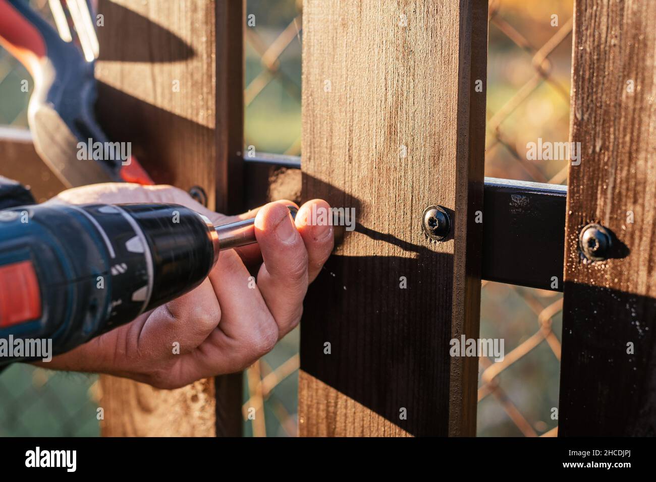 Hand of carpenter holding stud driving machine putting screw into ...