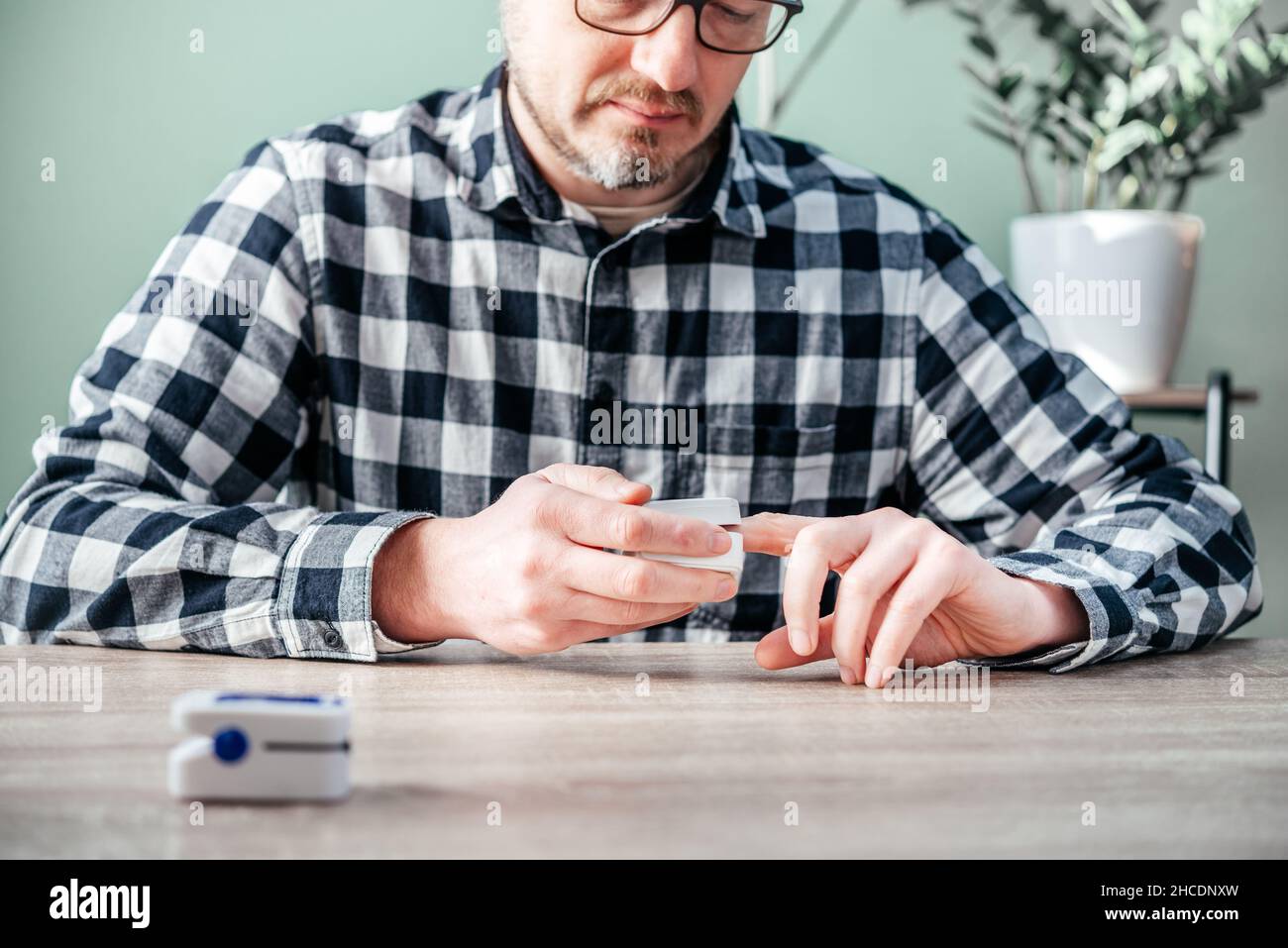 A man checking oxygen level at home with home oximeter, patient ...
