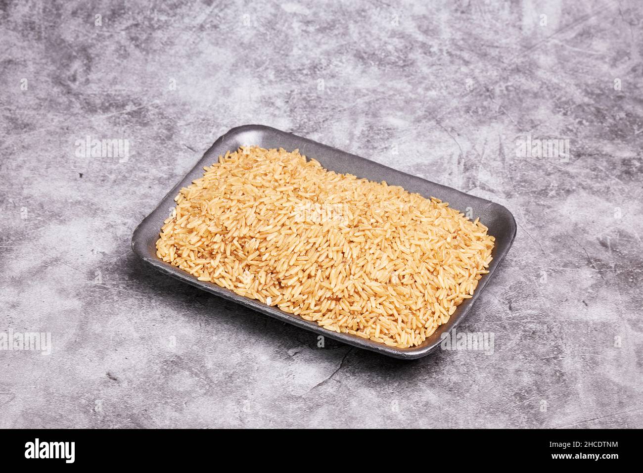 Black tray with raw rice on a gray stone background. Asian food ...