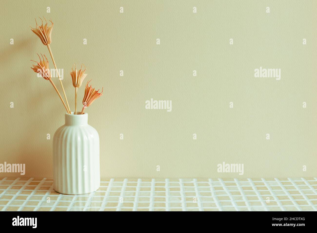 Vase of pink dry flowers on ceramic mosaic tile table. beige wall ...