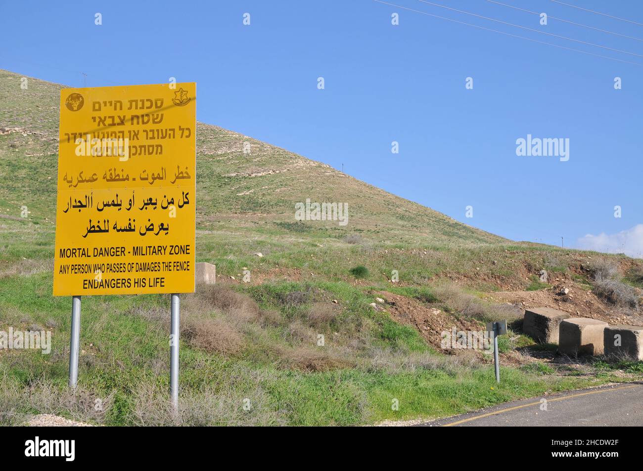 Israel, Golan Heights. The Syrian Israeli border fence a yellow warning ...