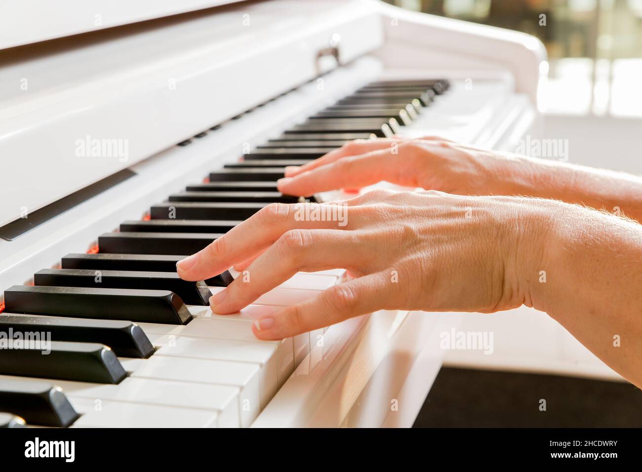 fingers and hands of a woman playing a white piano Stock Photo - Alamy