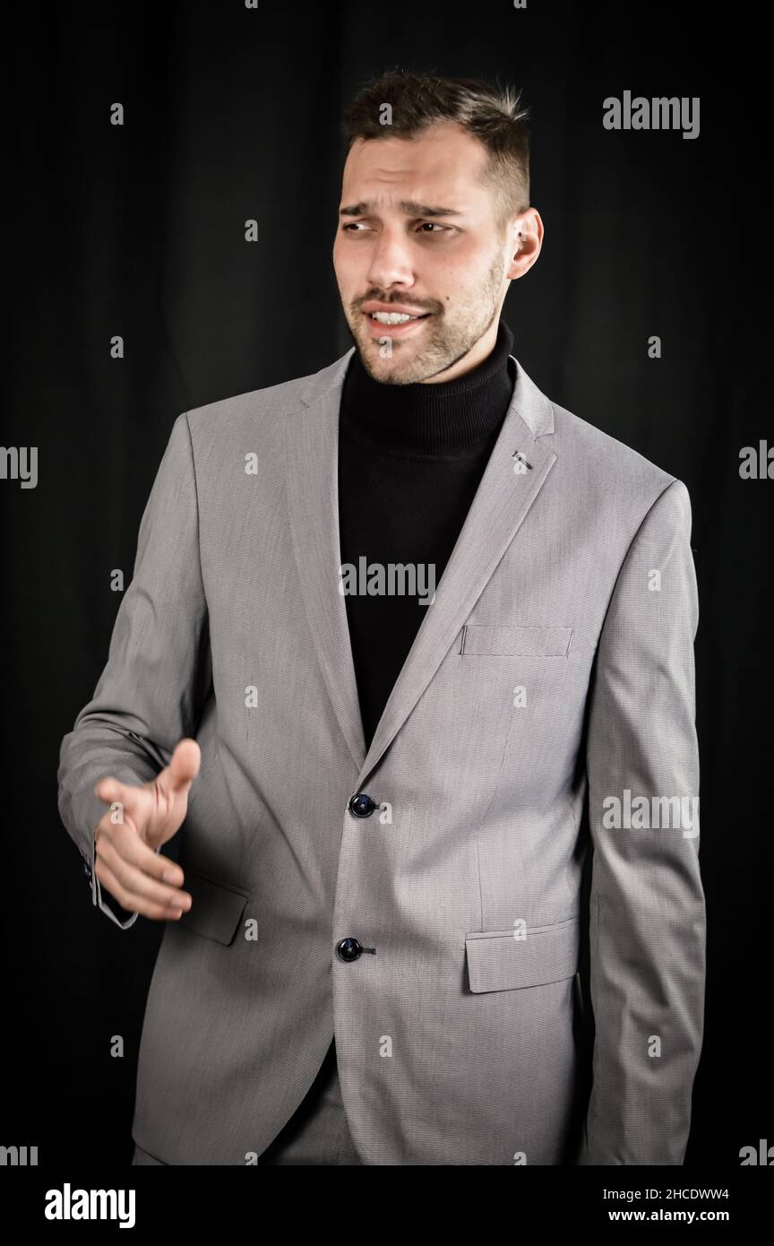 portrait of a young businessman in a gray business suit gesturing with ...