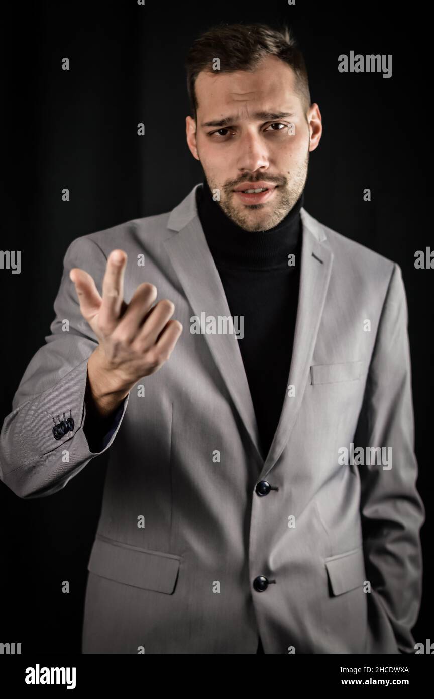 portrait of a young businessman in a gray business suit gesturing with ...
