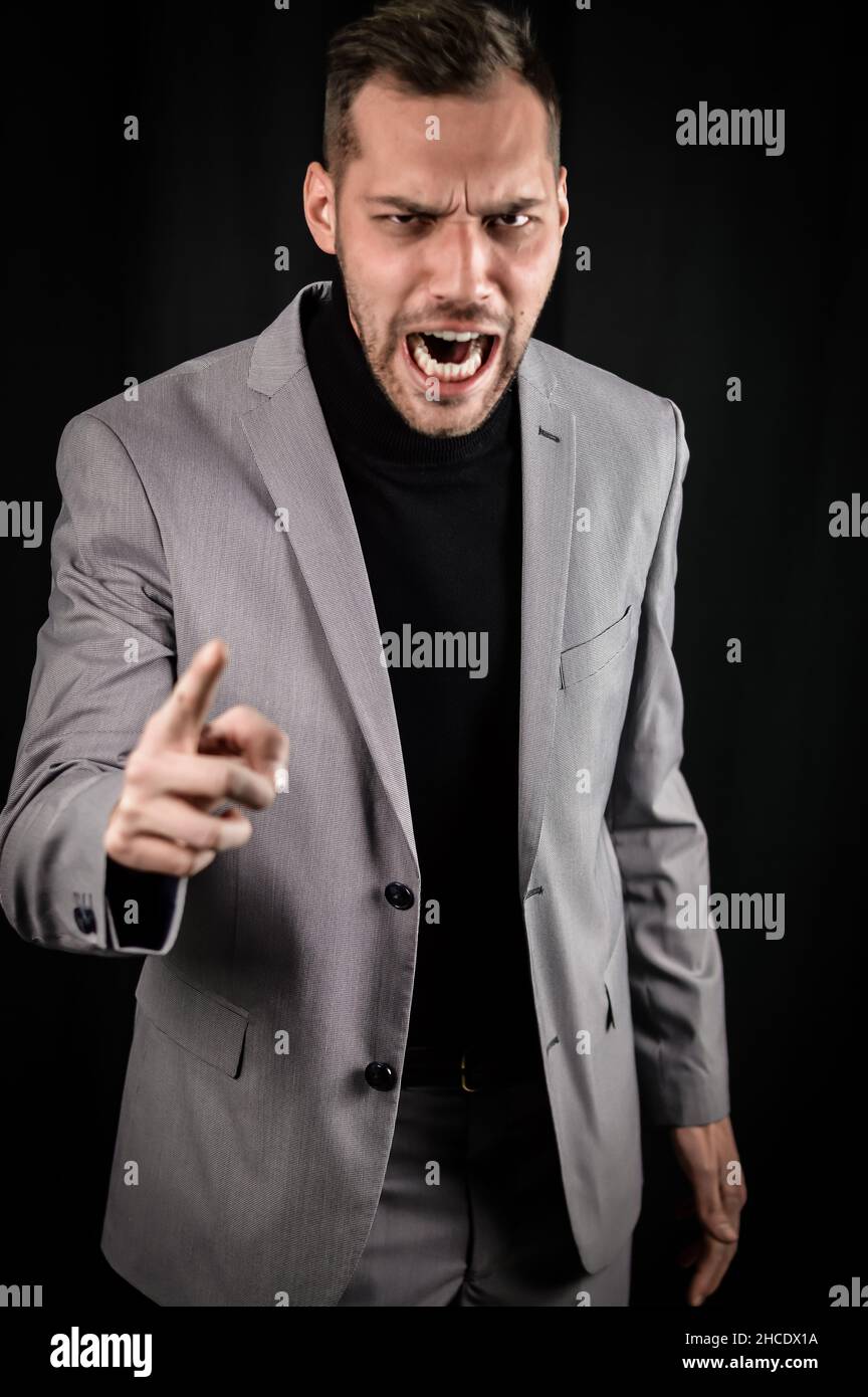 portrait of a young businessman in a gray suit, very angry yelling and ...